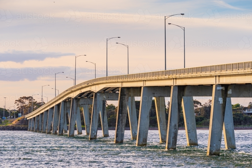 Image of A row of concrete pylons supporting a long bridge over a ...