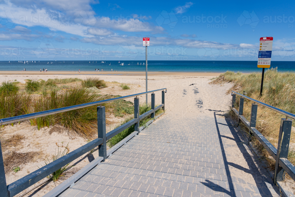 Image of A small bridge with railings leading over the sand to a wide ...