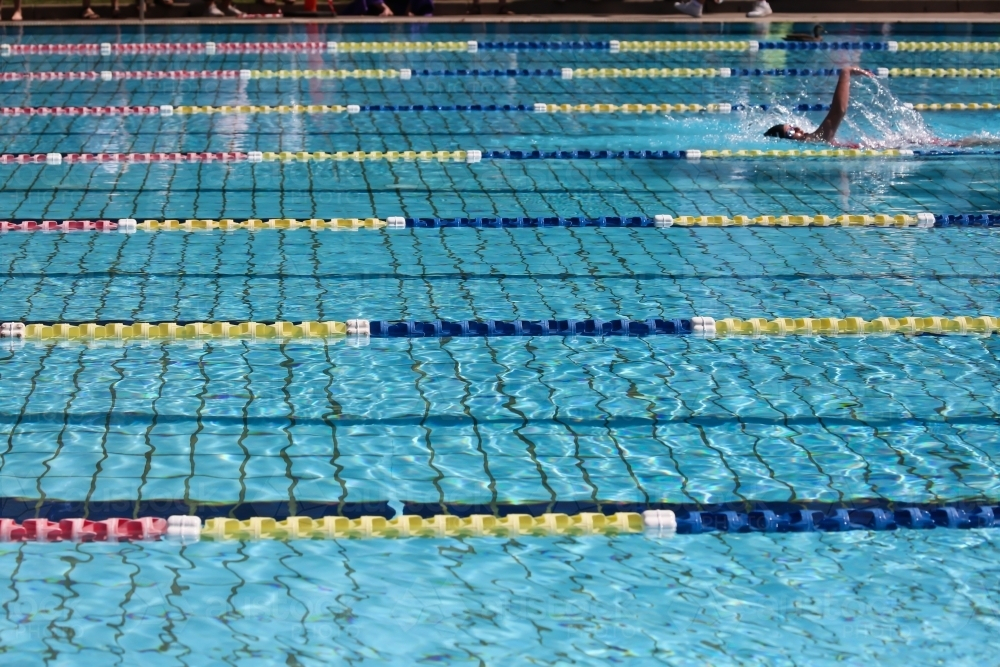 Image of A swimmer in a large public pool with floating lane dividers ...