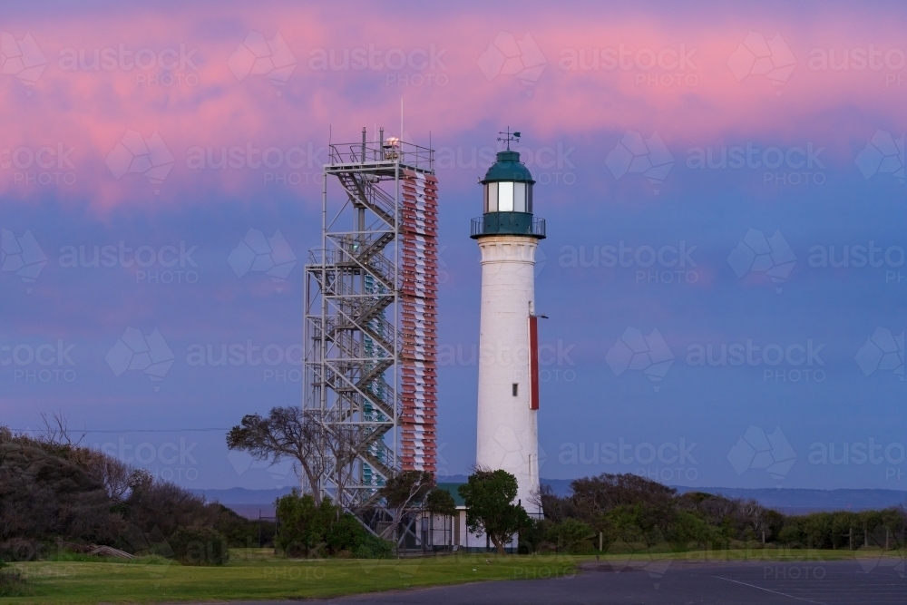 Image of A tall white lighthouse and adjacent light tower against a ...