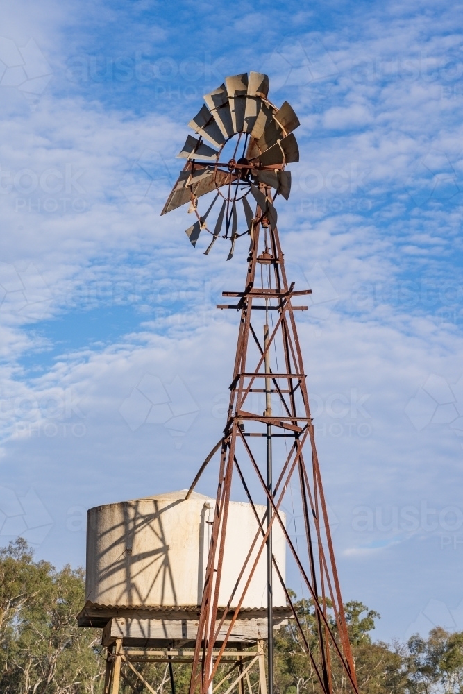 Image of A tall windmill standing next to a water tank - Austockphoto Image of A tall windmill standing next to a water tank - Austockphoto