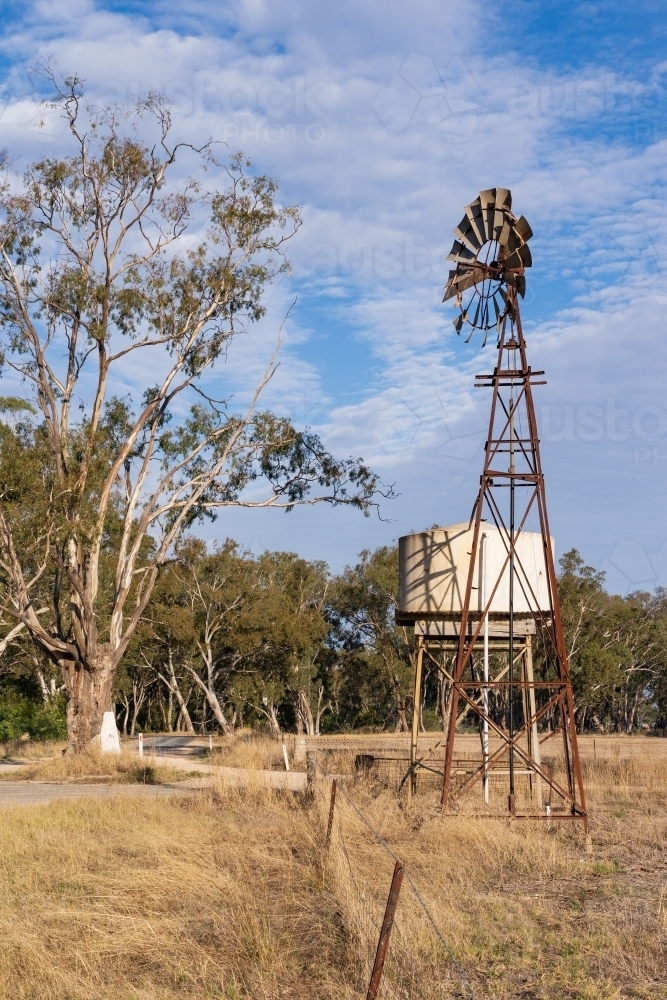 Image of A tall windmill standing next to a water tank in a rural ...