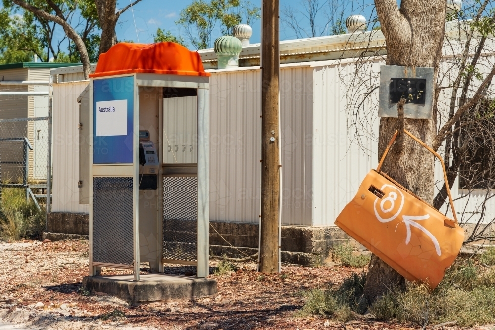 Image of A telephone booth next a car door hanging on a tree in an ...