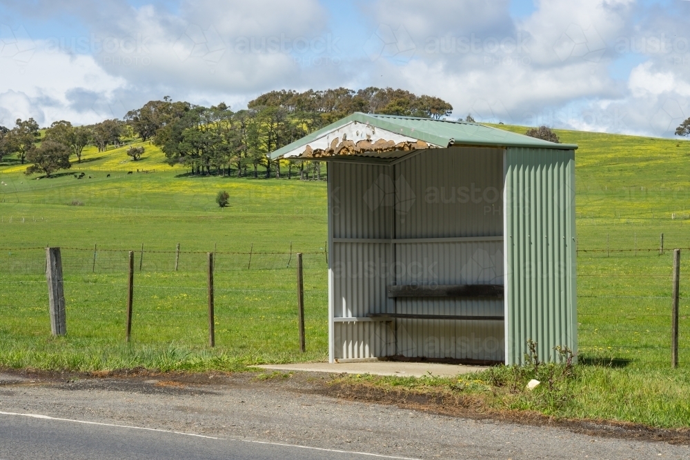 Image of A tin bus shelter on a country road below green hills ...