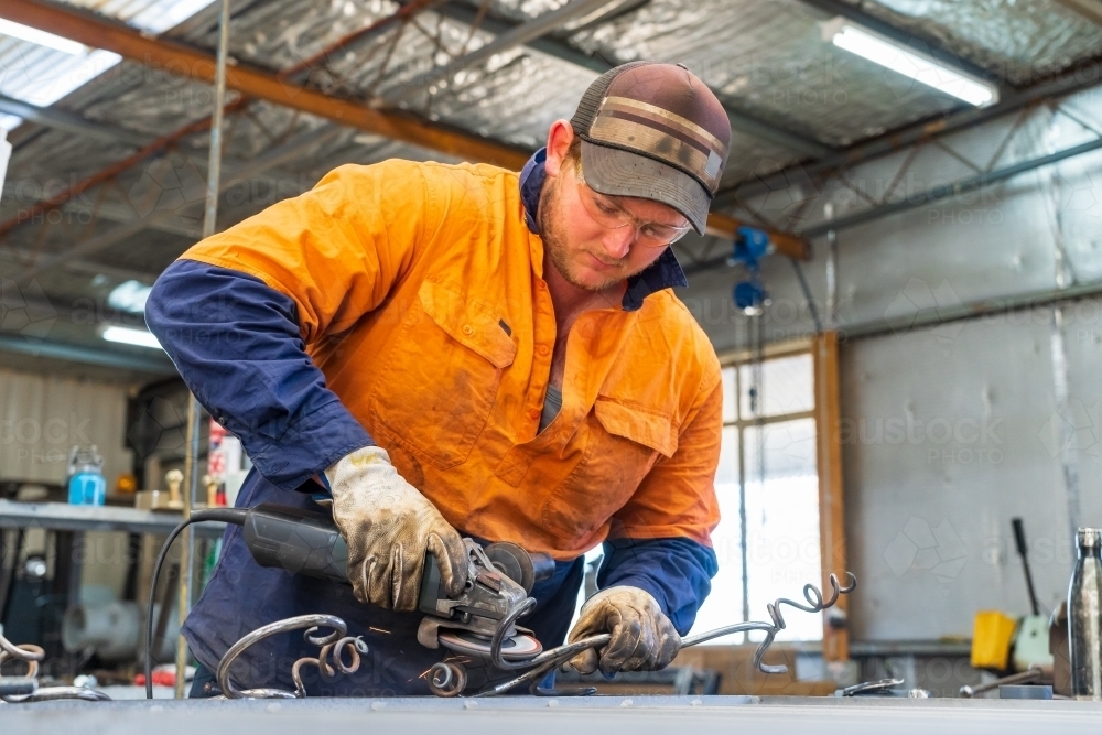 Image of A tradesman wearing high vis clothing grinding steel on a ...