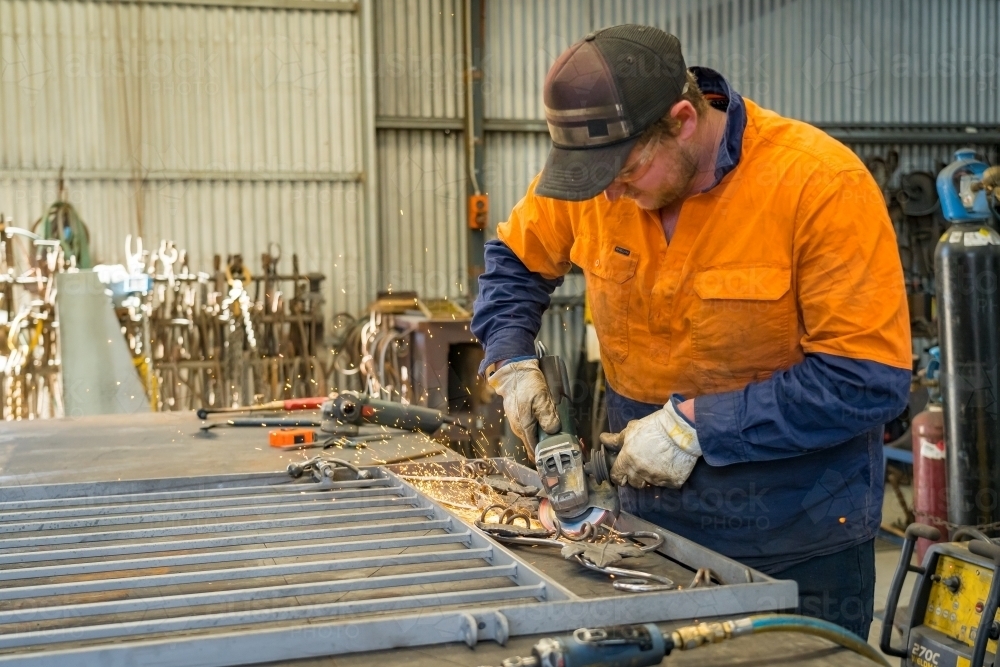 Image of A tradesman wearing high vis clothing grinding steel on a ...