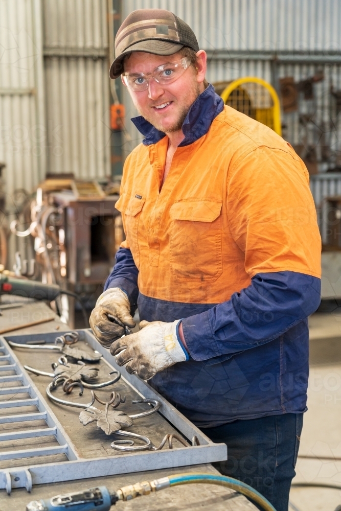 Image of A tradesman wearing high vis clothing,standing at a work bench ...