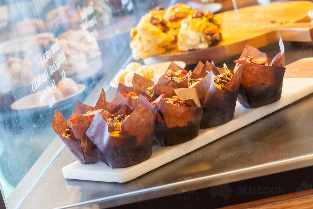 Image of A tray of baked muffins in a display case - Austockphoto