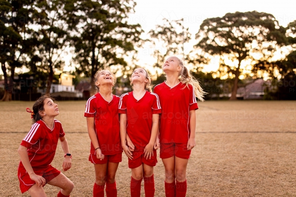 Image of A tween girls football team looking up waiting for a ball to ...