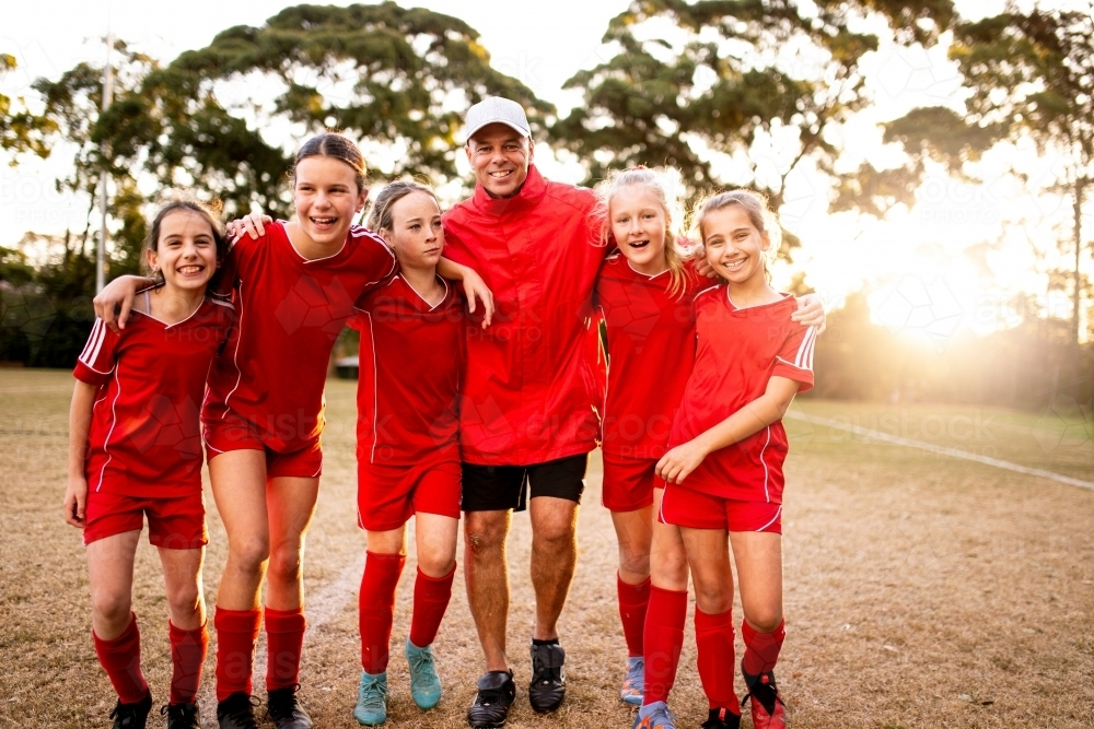 Image of A tween girls football team members walking with their coach ...