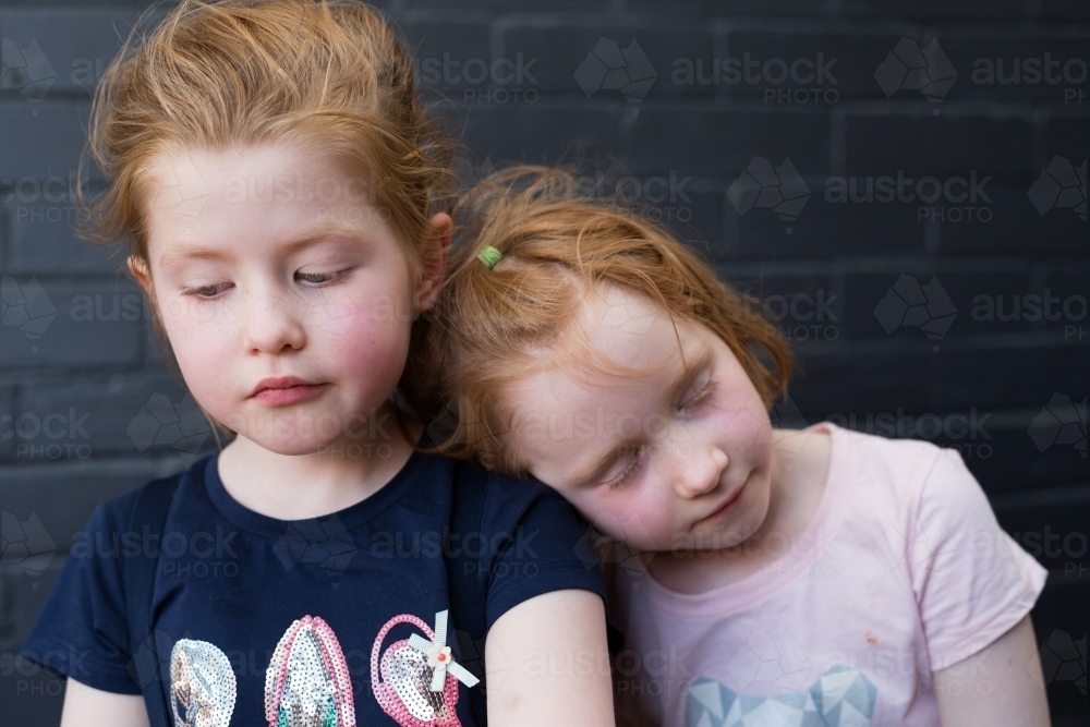 Image of A twin with her head leaning on her sisters shoulder ...