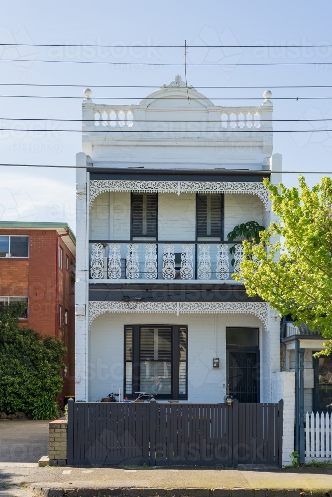 Image of A two storey terrace house with a picket fence and wrought ...