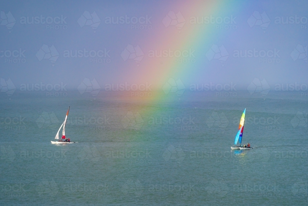 Image of A vivid rainbow between two yachts on a wide blue ocean ...