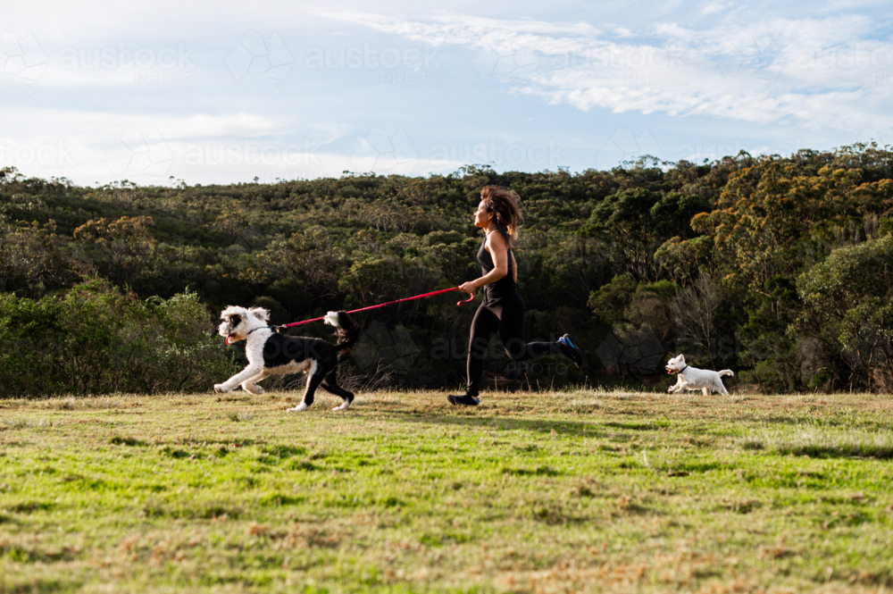 Image of A woman jogs across a lush green field, happily exercising ...