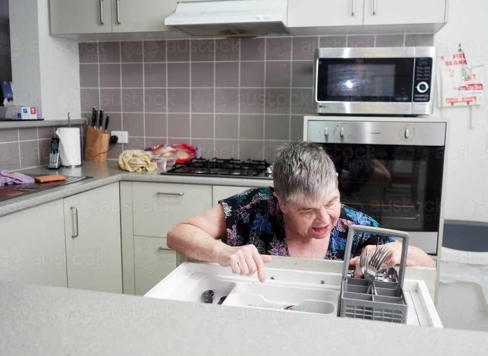 Image of A woman seated on a walking frame, sorting cutlery in a group ...