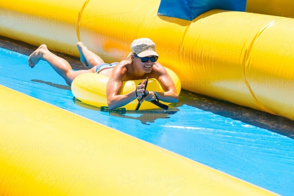 Image of A woman slides down a waterslide - Austockphoto
