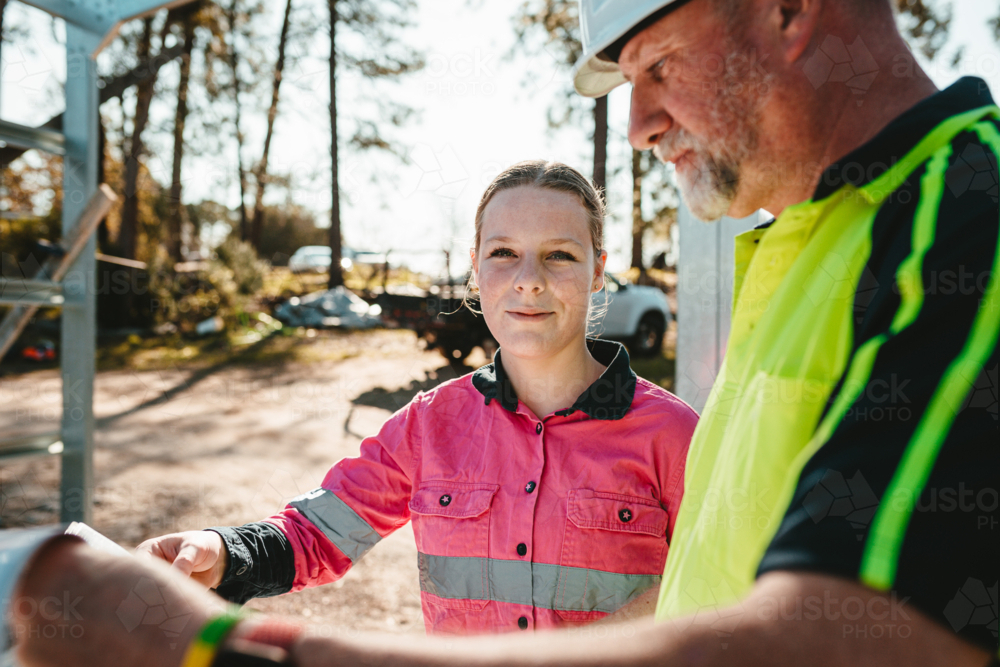 Image of A young woman apprentice with foreman looking at the ...