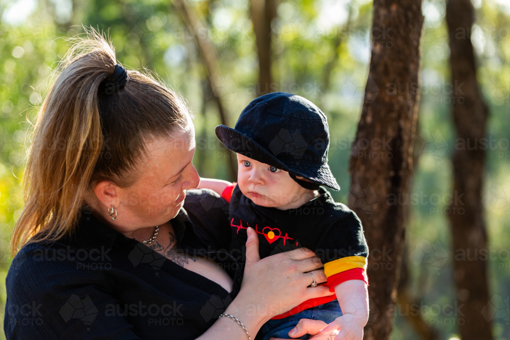 Image of Aboriginal Australian mum carrying baby boy wearing bucket hat ...
