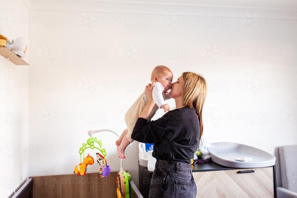 Image of Aboriginal Australian mum lifting baby up in bedroom giving ...