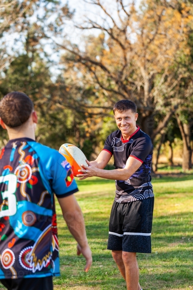 Image of Aboriginal Australian teammates practicing footy passes in ...