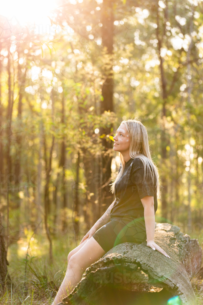 Image of Aboriginal Australian woman sitting on log with hopeful ...