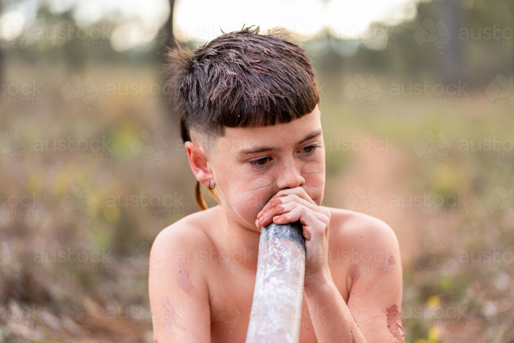 Image of aboriginal child playing didgeridoo wearing traditional ochre ...