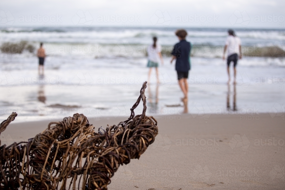 Image of Aboriginal family playing in the ocean behind a traditional ...
