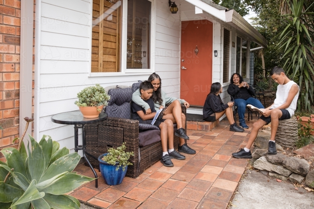 Image of Aboriginal family sitting together on back porch - Austockphoto