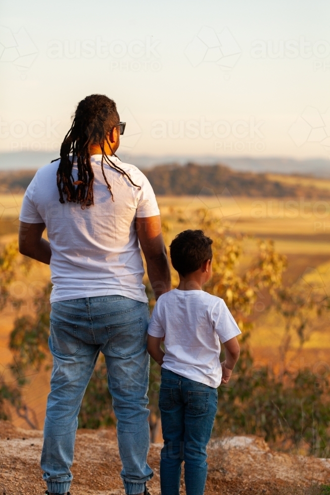 Image of Aboriginal father and son standing on edge of cliff looking ...