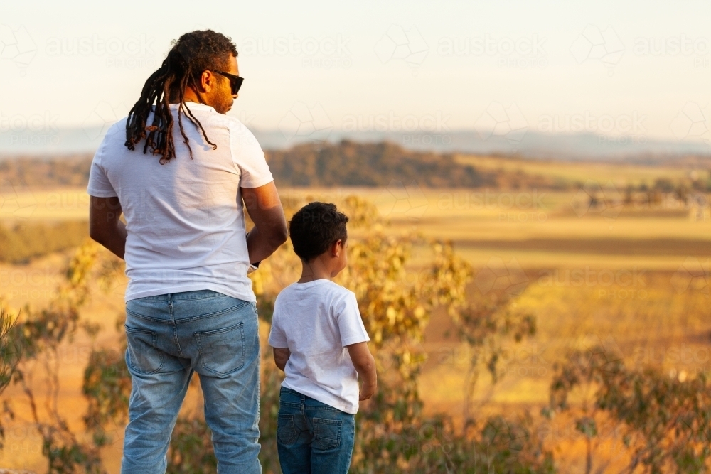 Image of Aboriginal father and son standing on edge of cliff looking ...