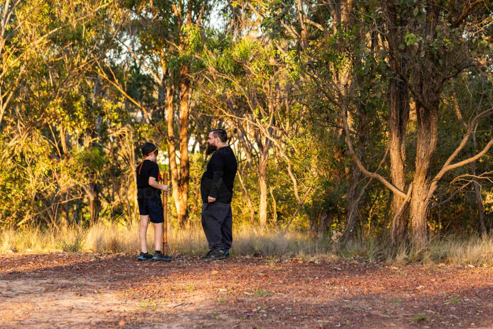 Image of Aboriginal father and son talking together in golden light in ...