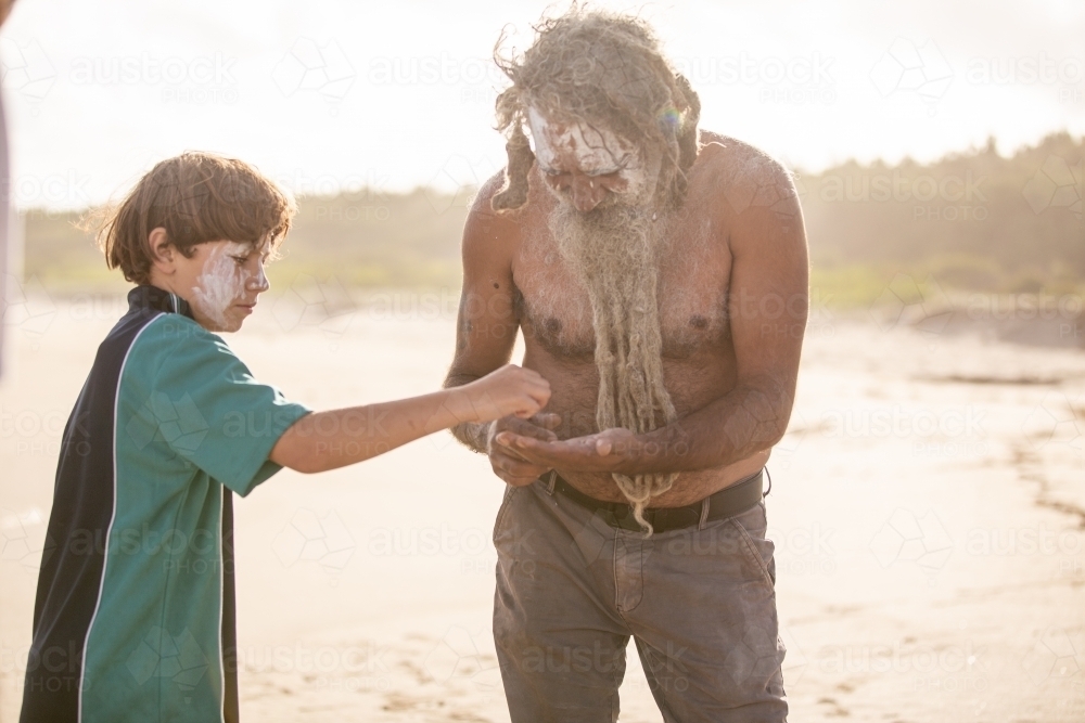 Image of Aboriginal father helping son on a beach - Austockphoto