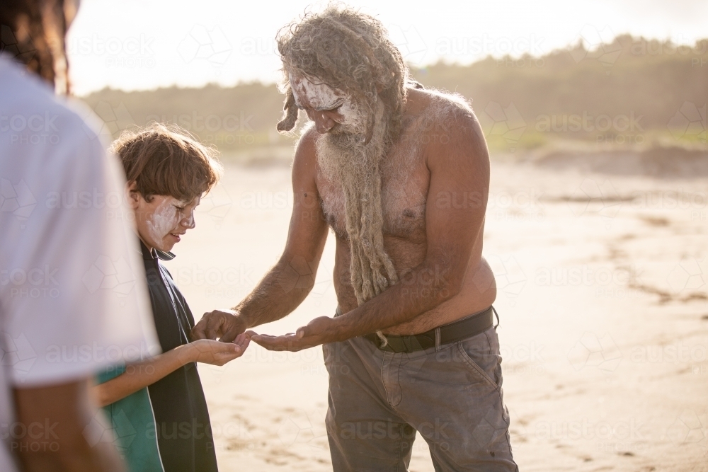 Image of Aboriginal father helping son on a beach - Austockphoto