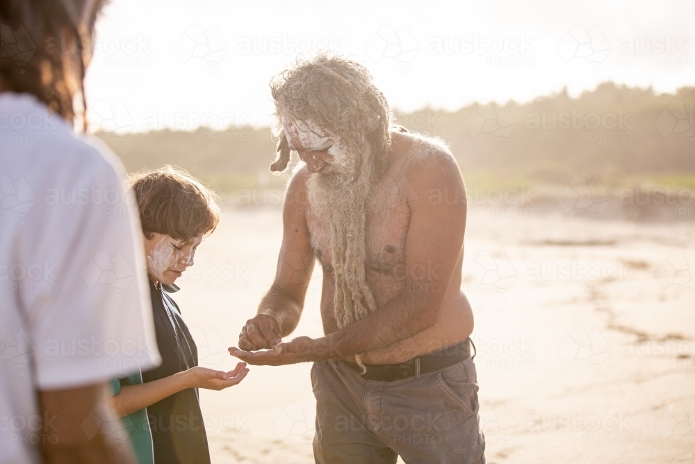Image of Aboriginal father helping son on a beach - Austockphoto
