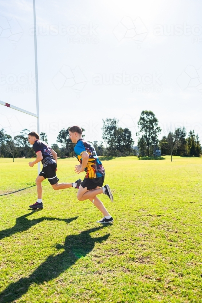 Image of Aboriginal football players running on sports ground field in ...