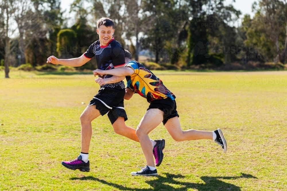 Image of Aboriginal football players running on sports ground field ...