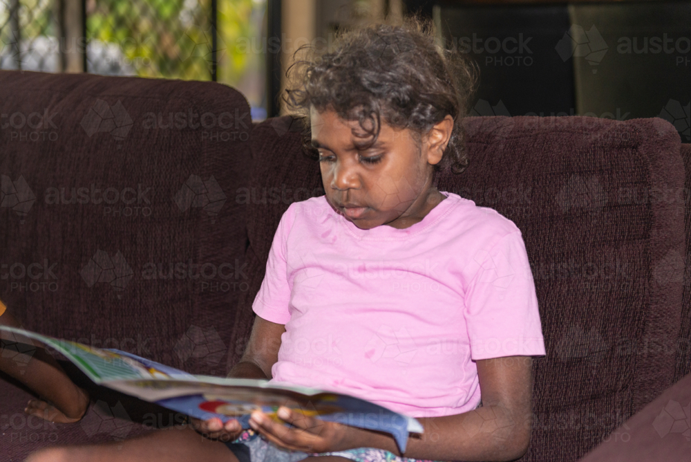 Image of Aboriginal girl reading a book focus behind subject - Austockphoto
