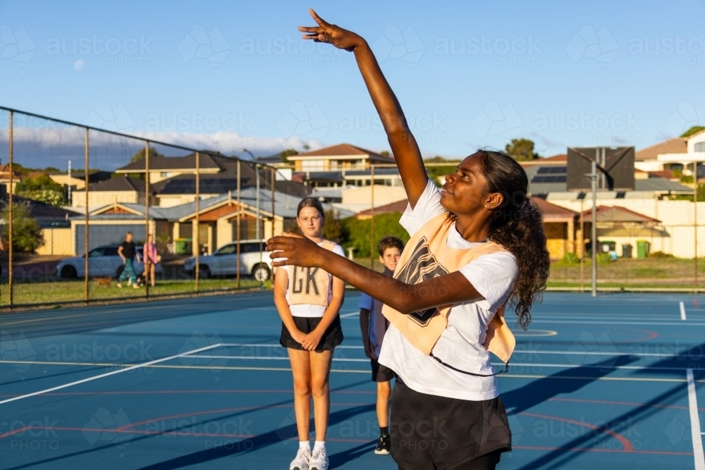 Image of aboriginal girl shooting goal in netball team - Austockphoto