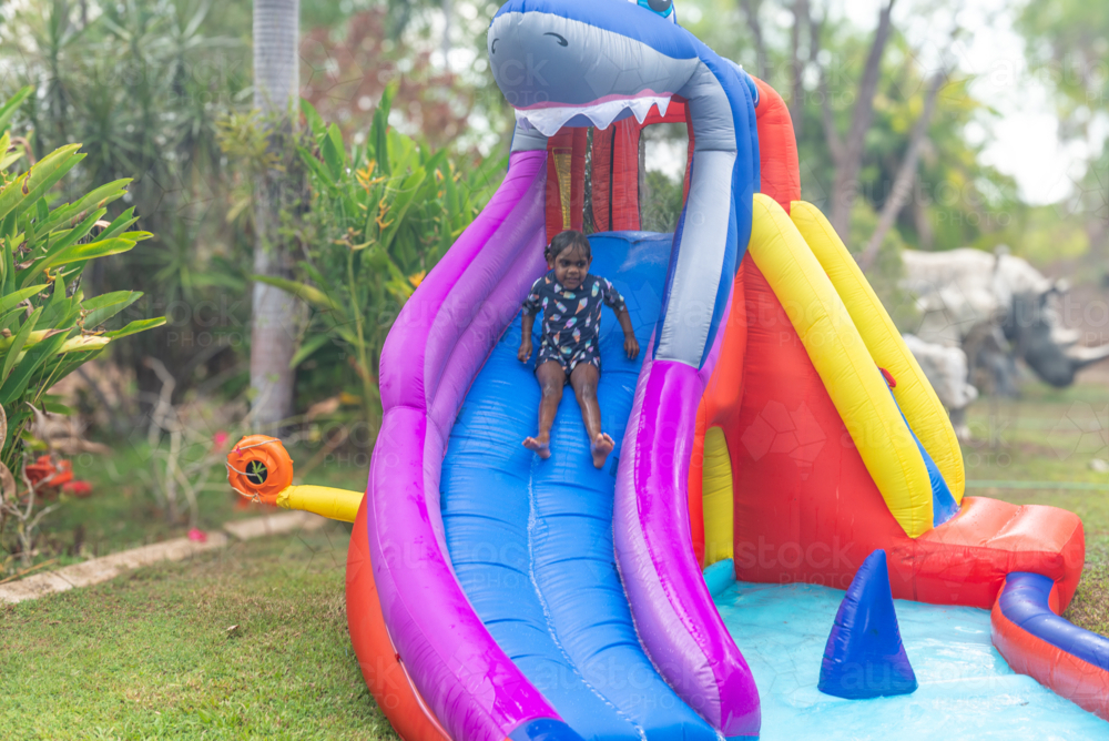 Image of Aboriginal girl sliding down a water slide - Austockphoto
