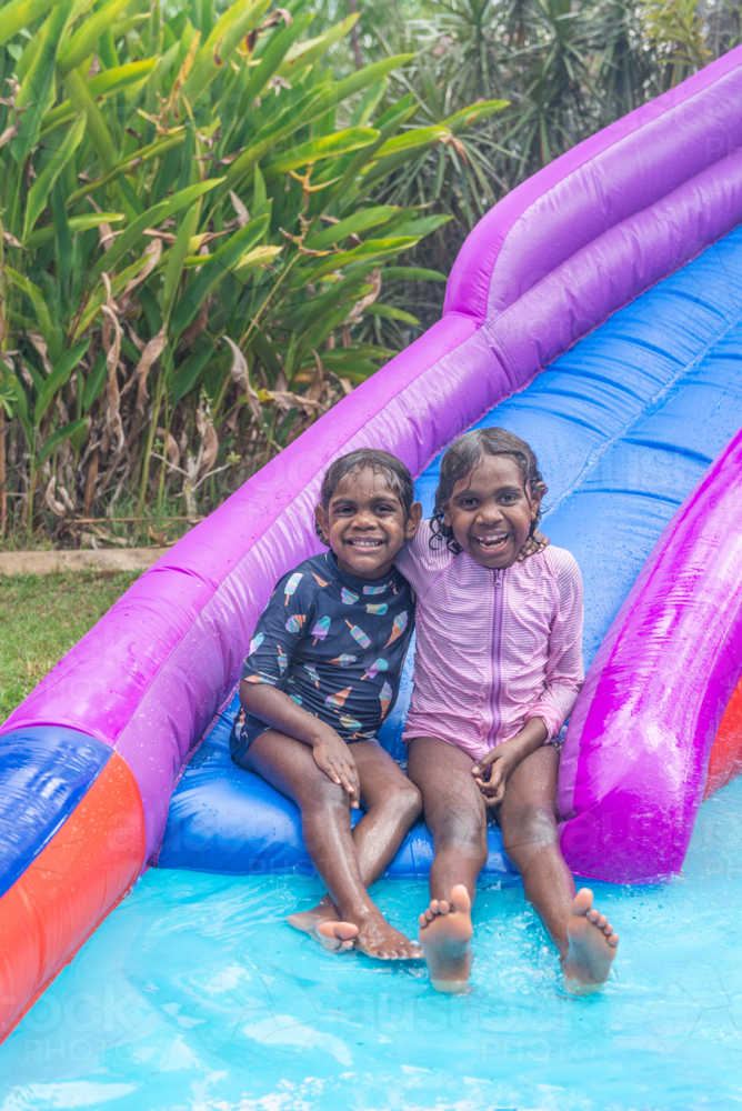 Image of Aboriginal girls on colourful water slide - Austockphoto