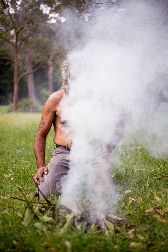 Image of Aboriginal man covered by smoke from a fire - Austockphoto