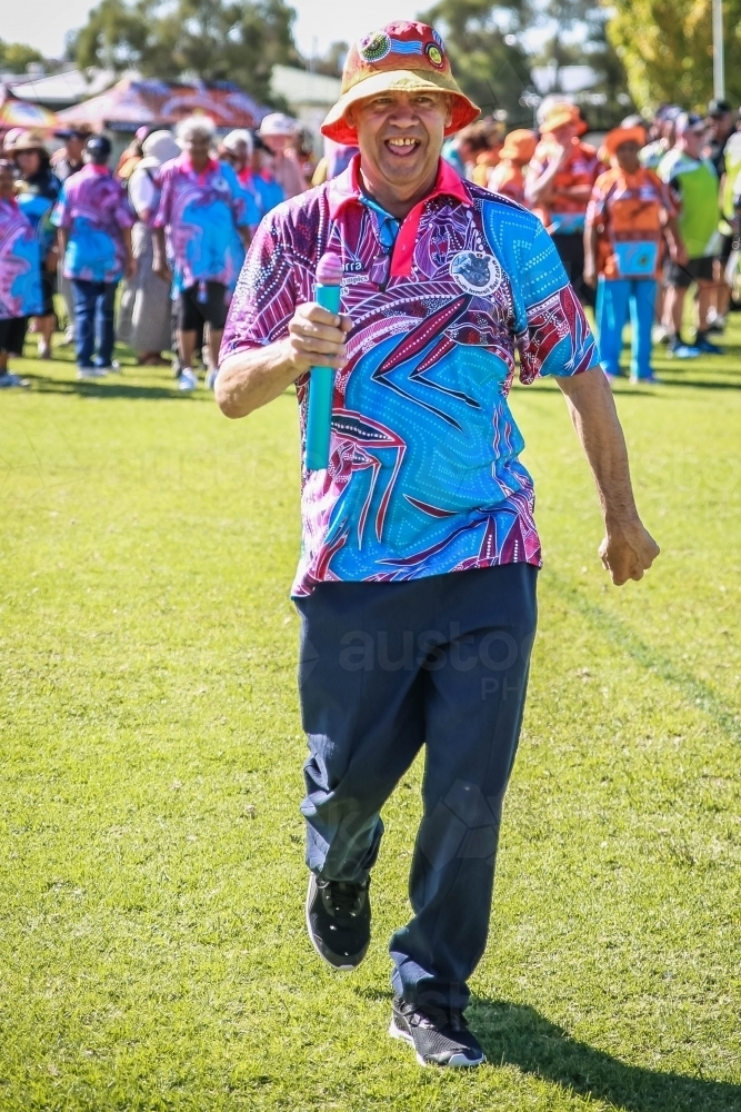 Image of Aboriginal man holding baton in relay race - Austockphoto
