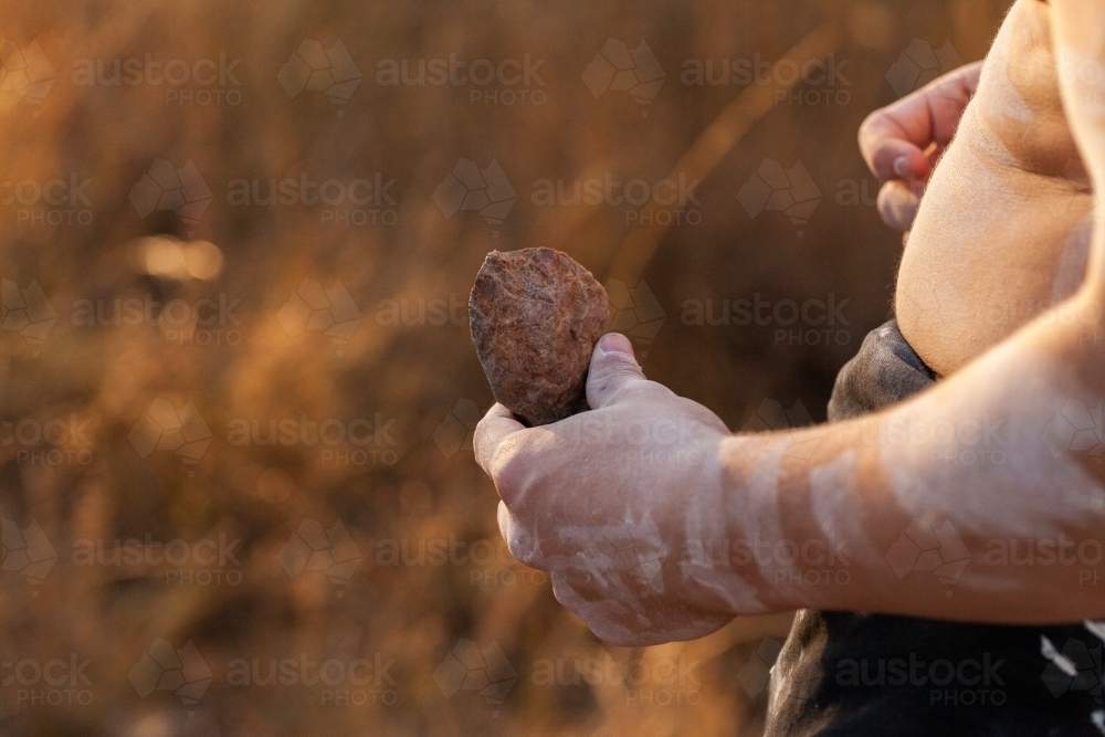 Image of Aboriginal man holding stone artefact from axe head in hand ...