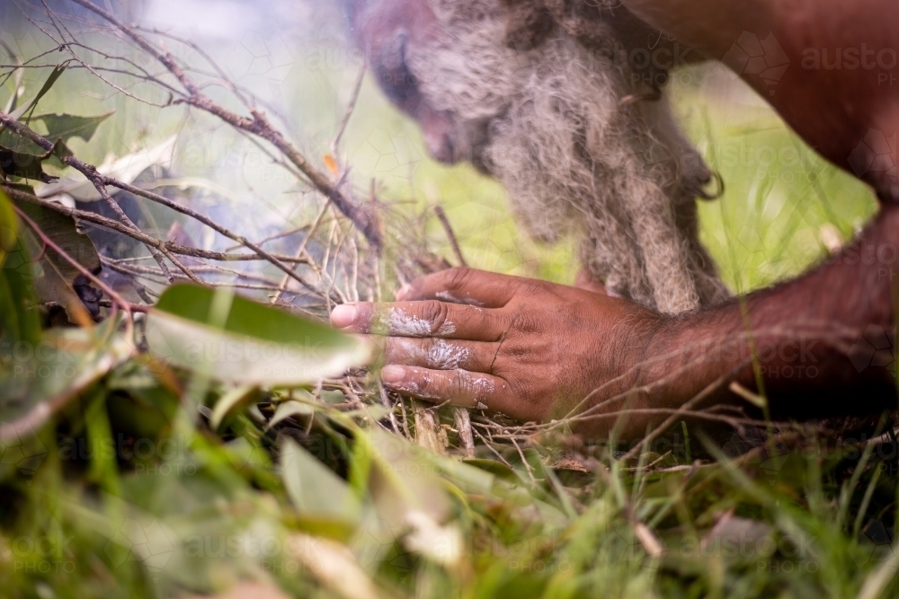 Image of Aboriginal man making a fire with sticks and leaves - Austockphoto