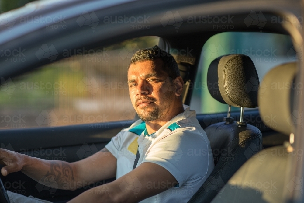 Image of Aboriginal man seen through passenger window driving a car ...