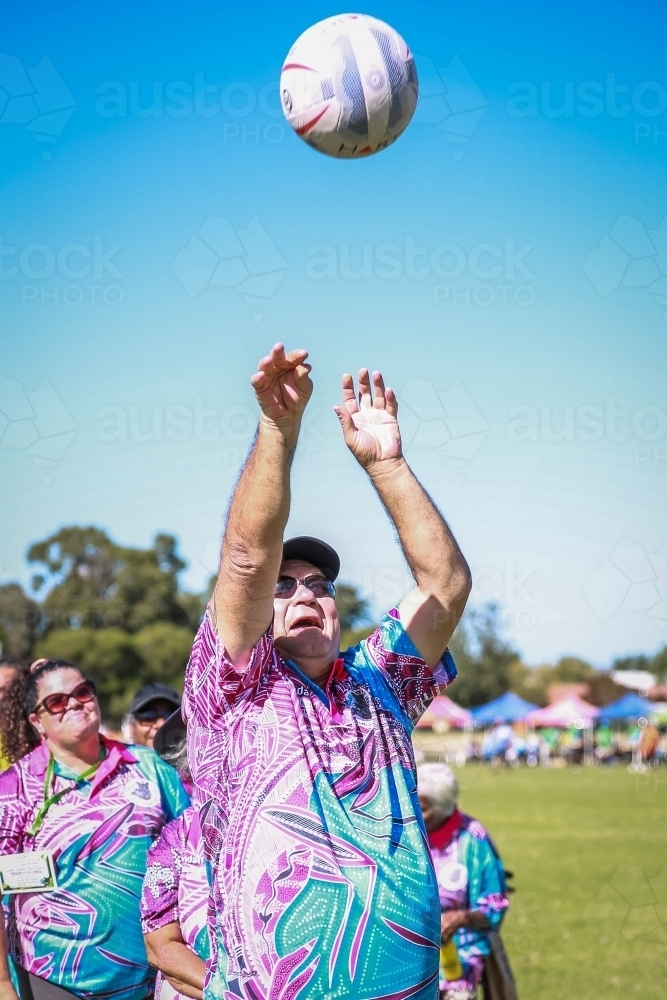 Image of Aboriginal man throwing netball in air - Austockphoto