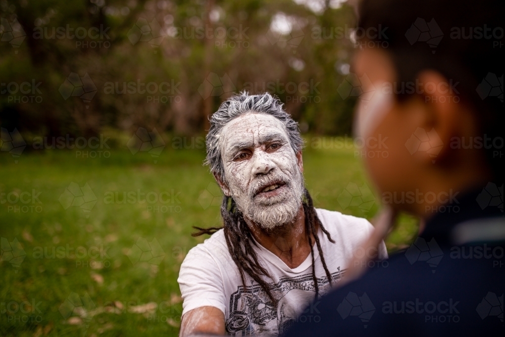 Image of Aboriginal man wearing white face paint talking to a young ...