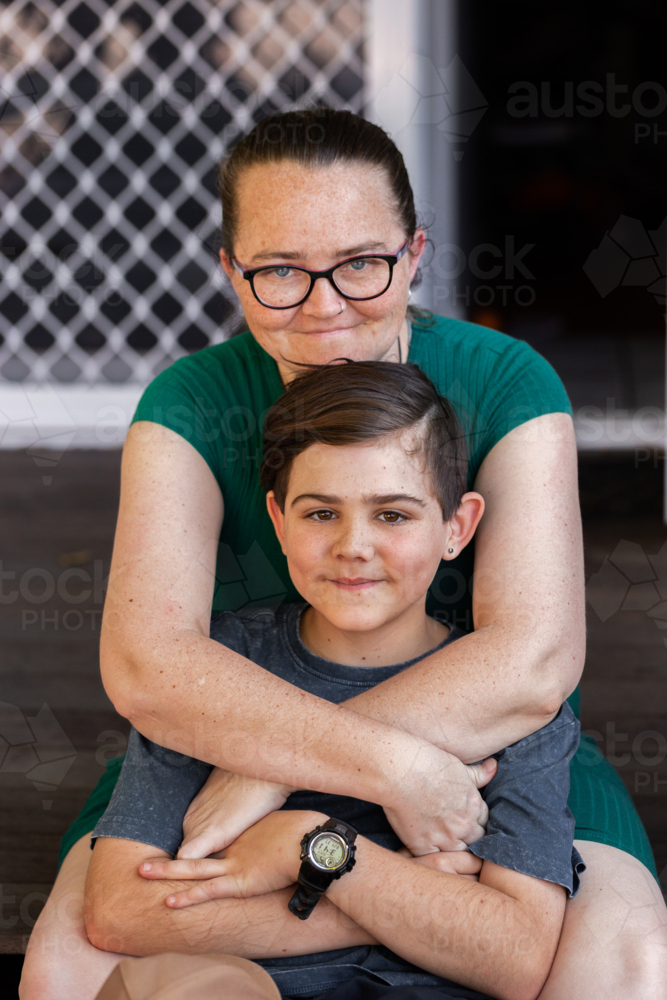 Image of Aboriginal mum with pre-teen son sitting together on steps of ...