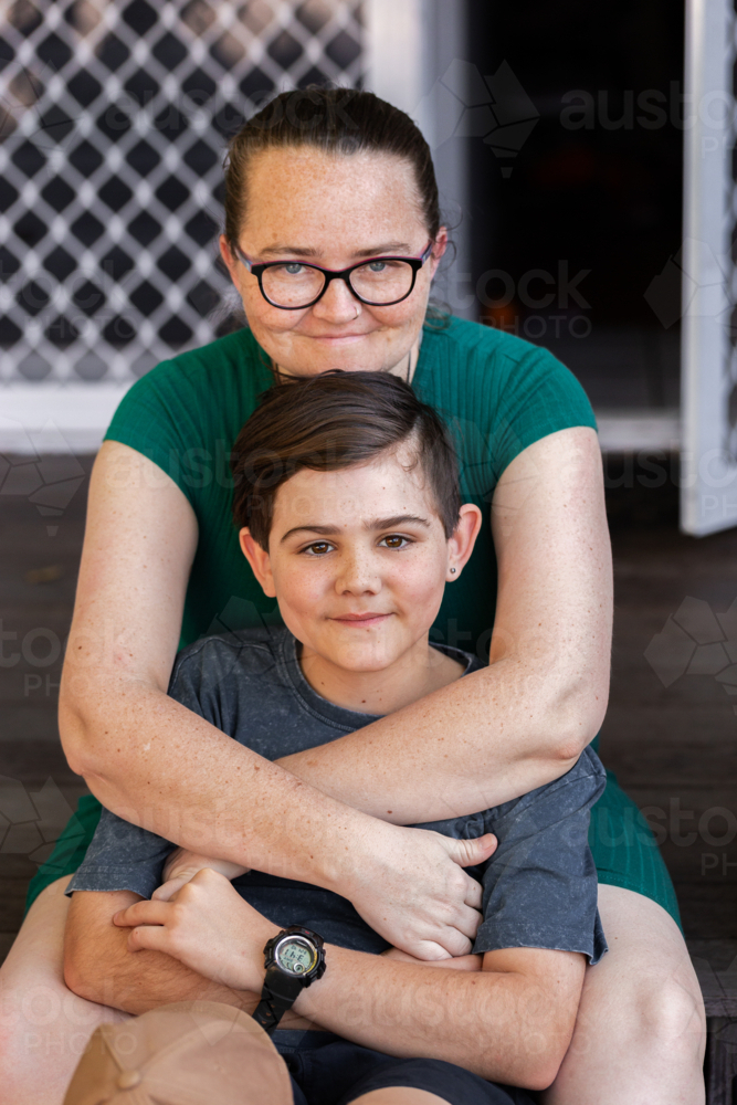 Image of Aboriginal mum with pre-teen son sitting together on steps of ...