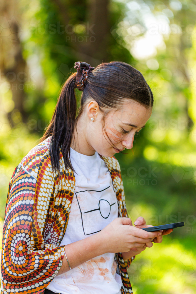 Image of Aboriginal teen girl using mobile phone while outside in ...